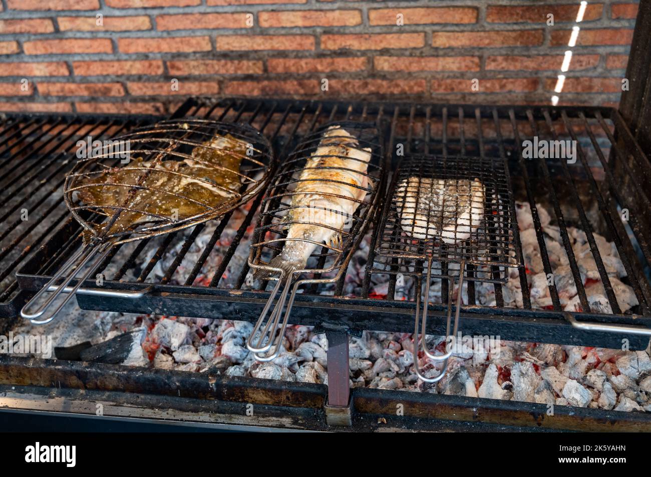 Fresh fish grilling on old charcoal parrillas white fish sea bass and ...