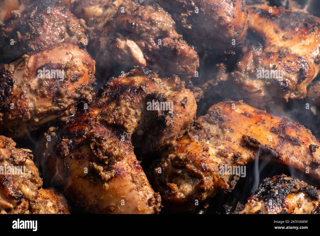 Grilling traditional Jamaican spicy jerk chicken with over charcoal ...