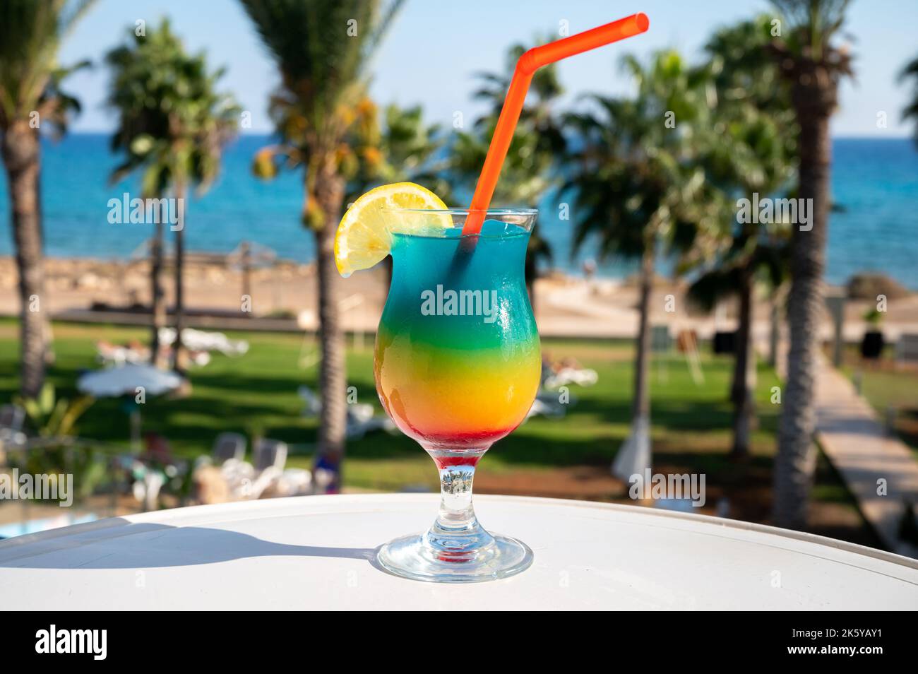 Colourful frozen Rainbow Paradise cocktail drink served in glass at ...