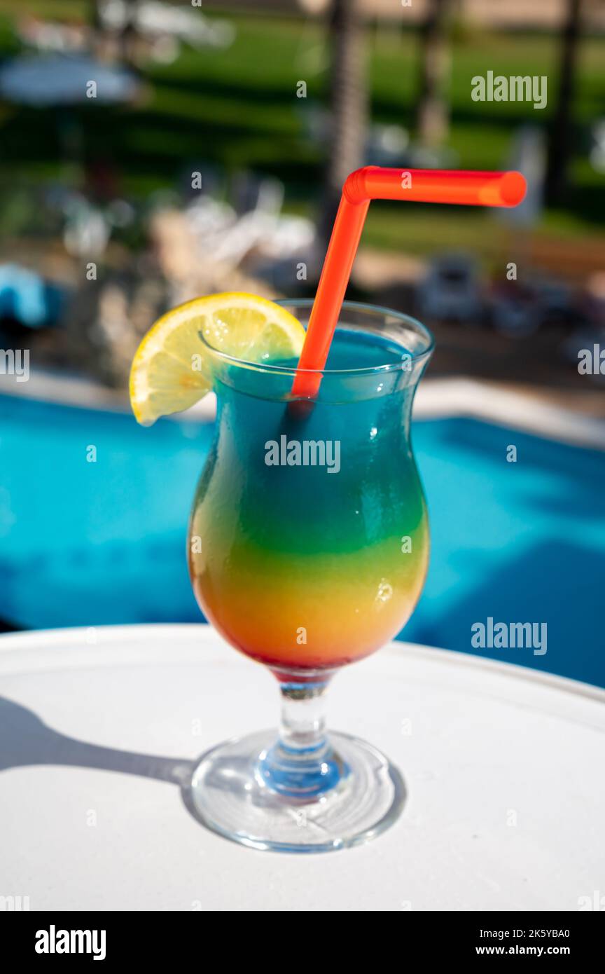 Colourful frozen Rainbow Paradise cocktail drink served in glass at ...