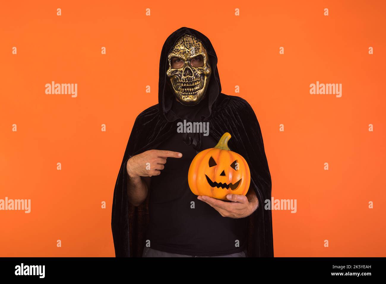 Person with skull mask and black hooded cape, holding and pointing ...