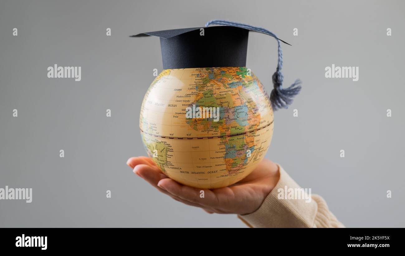 Woman holding a globe wearing a graduation cap Stock Photo - Alamy