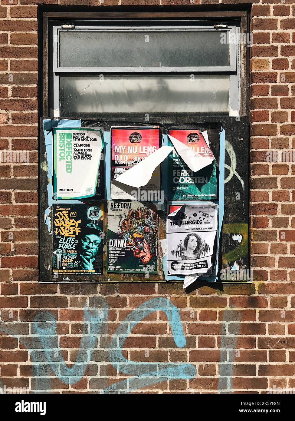 An urban brick wall with blue graffiti and a post box with concert ...