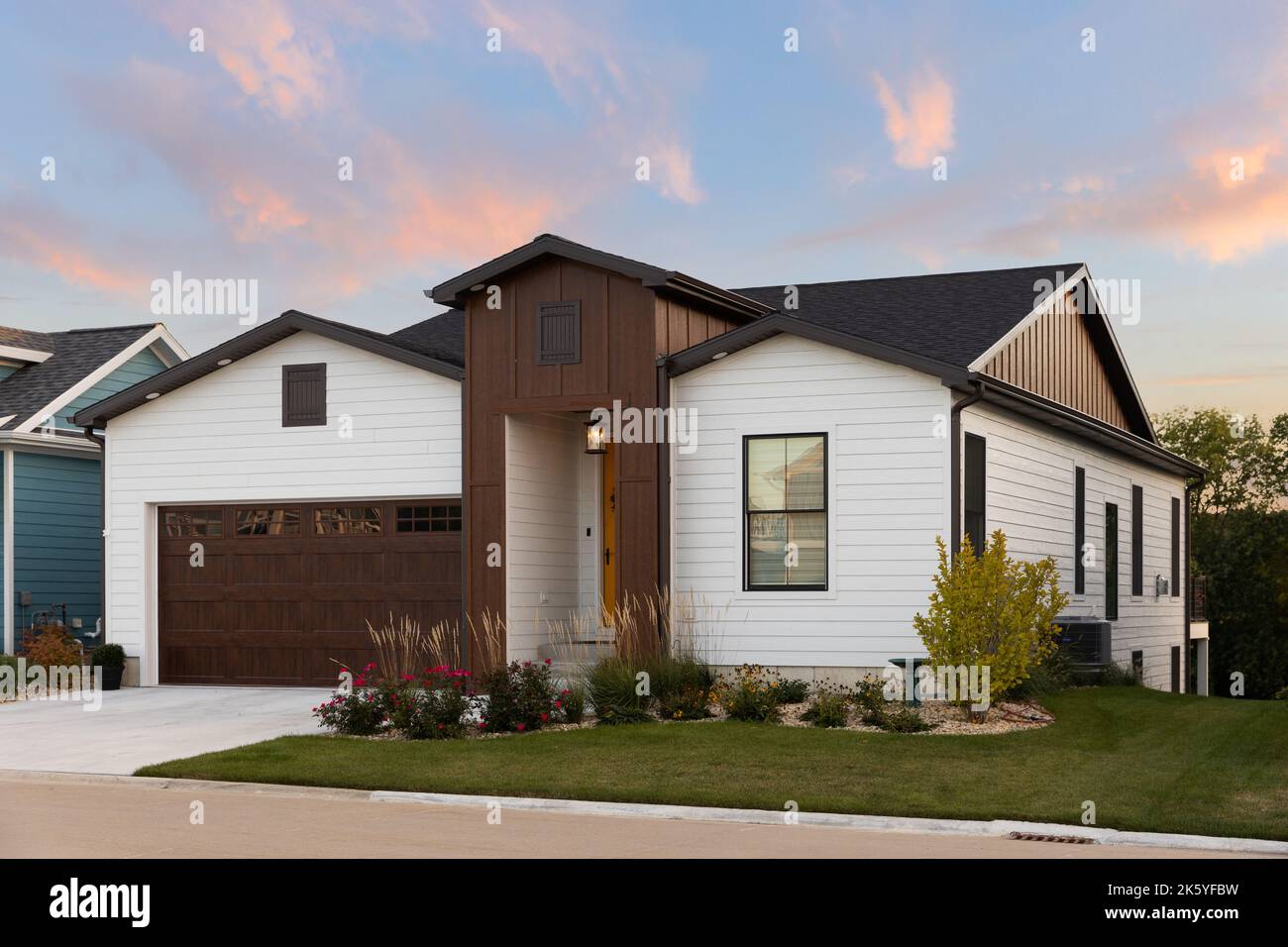 A beautiful modern home with white siding and wood accents, a yellow ...