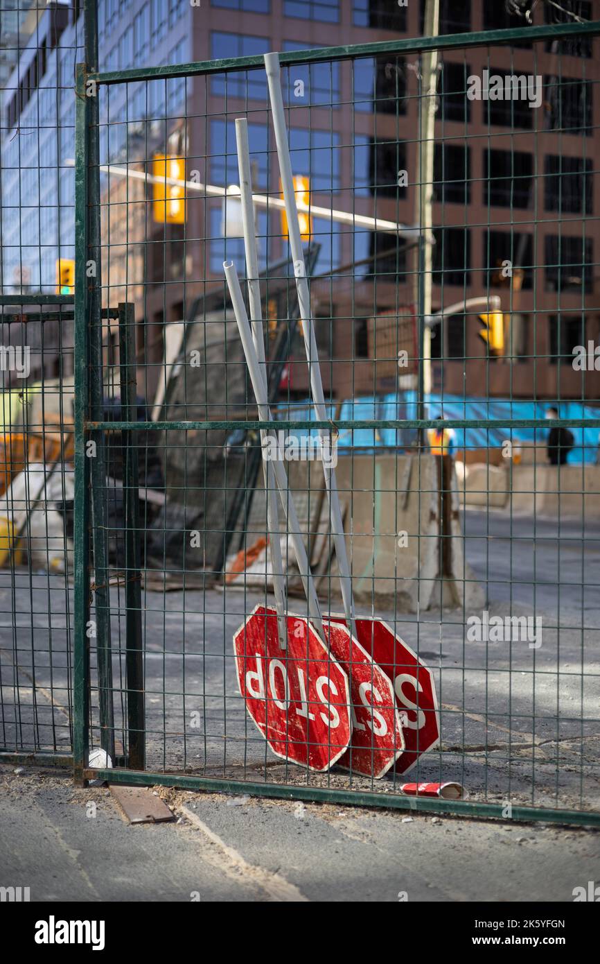 Upside down stop signs resting against a fence at a construction site ...