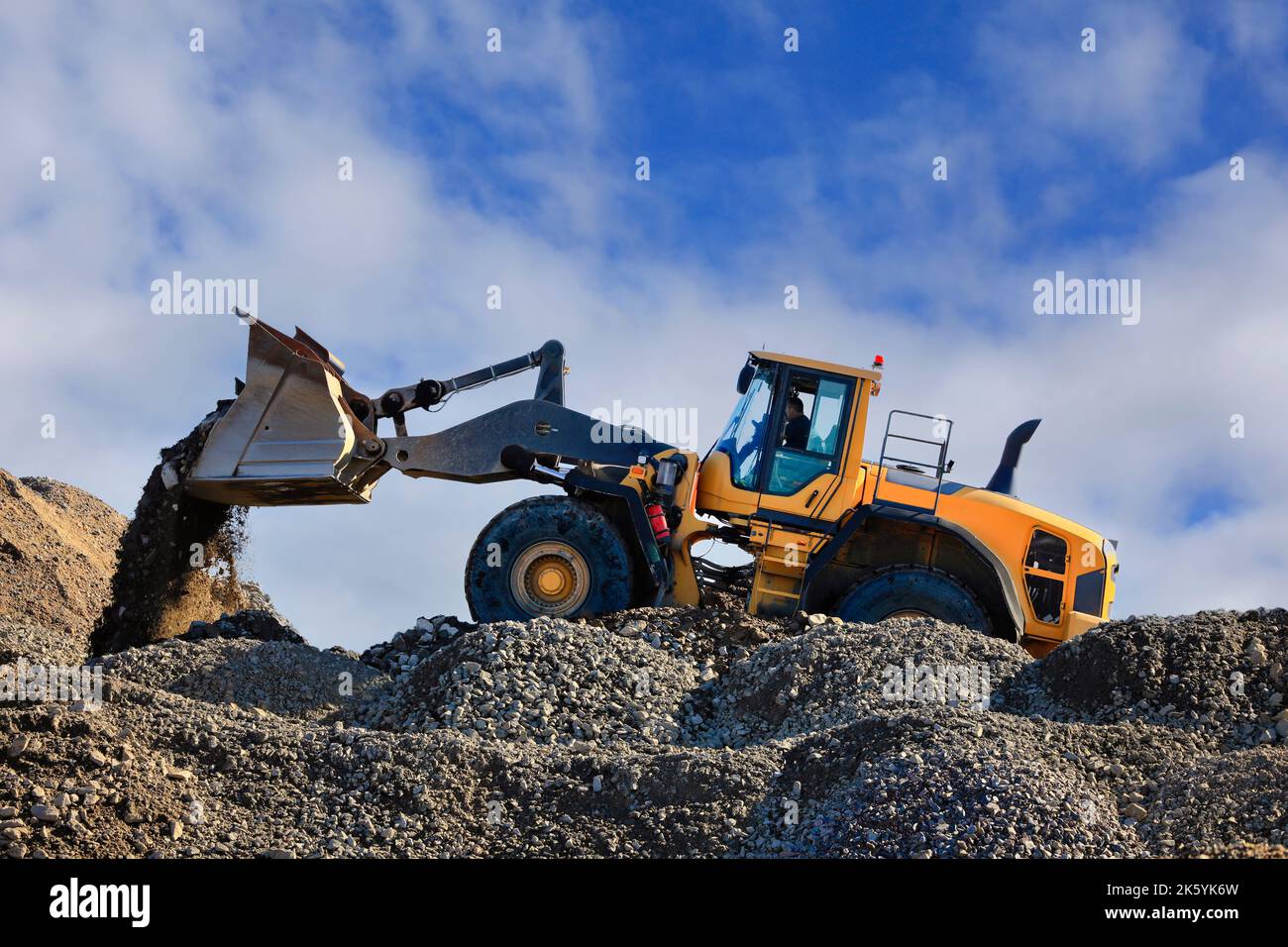 Yellow wheel loader working on top of a mound at construction site ...