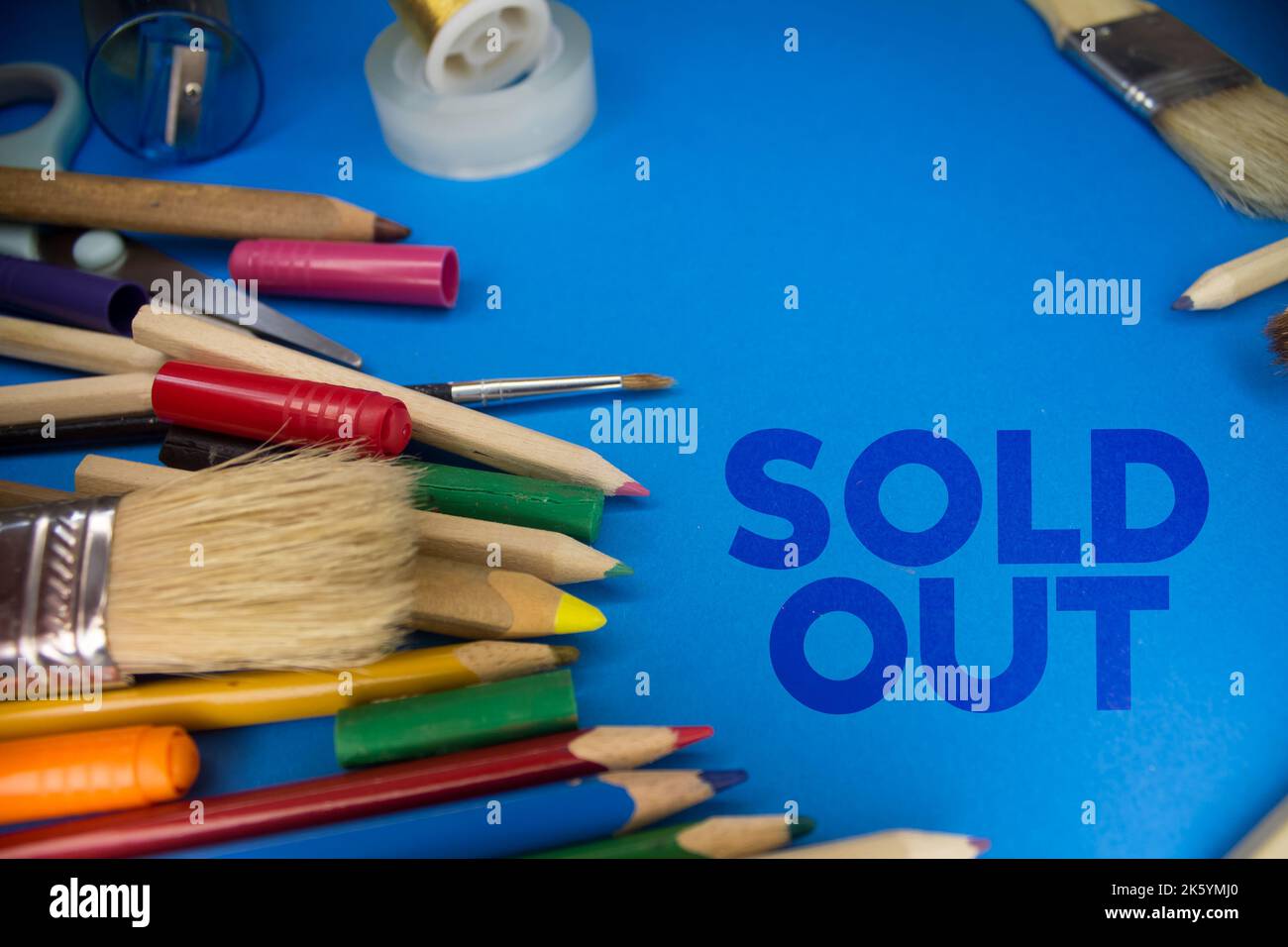 Overhead shot of school supplies with Sold Out text. Brushes, pencils ...
