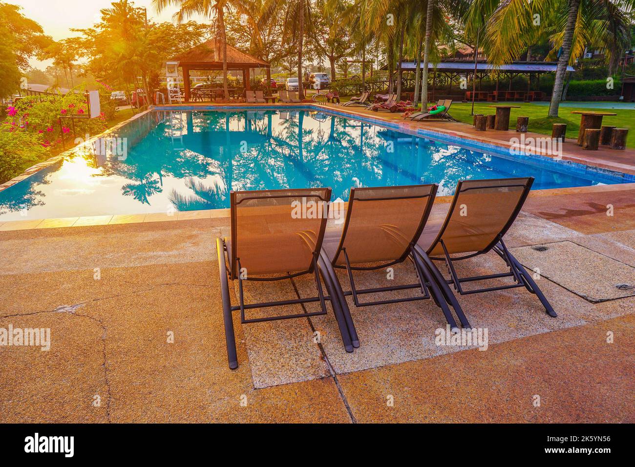 Relaxing on a bench beside swimming pool during sunrise Stock Photo - Alamy