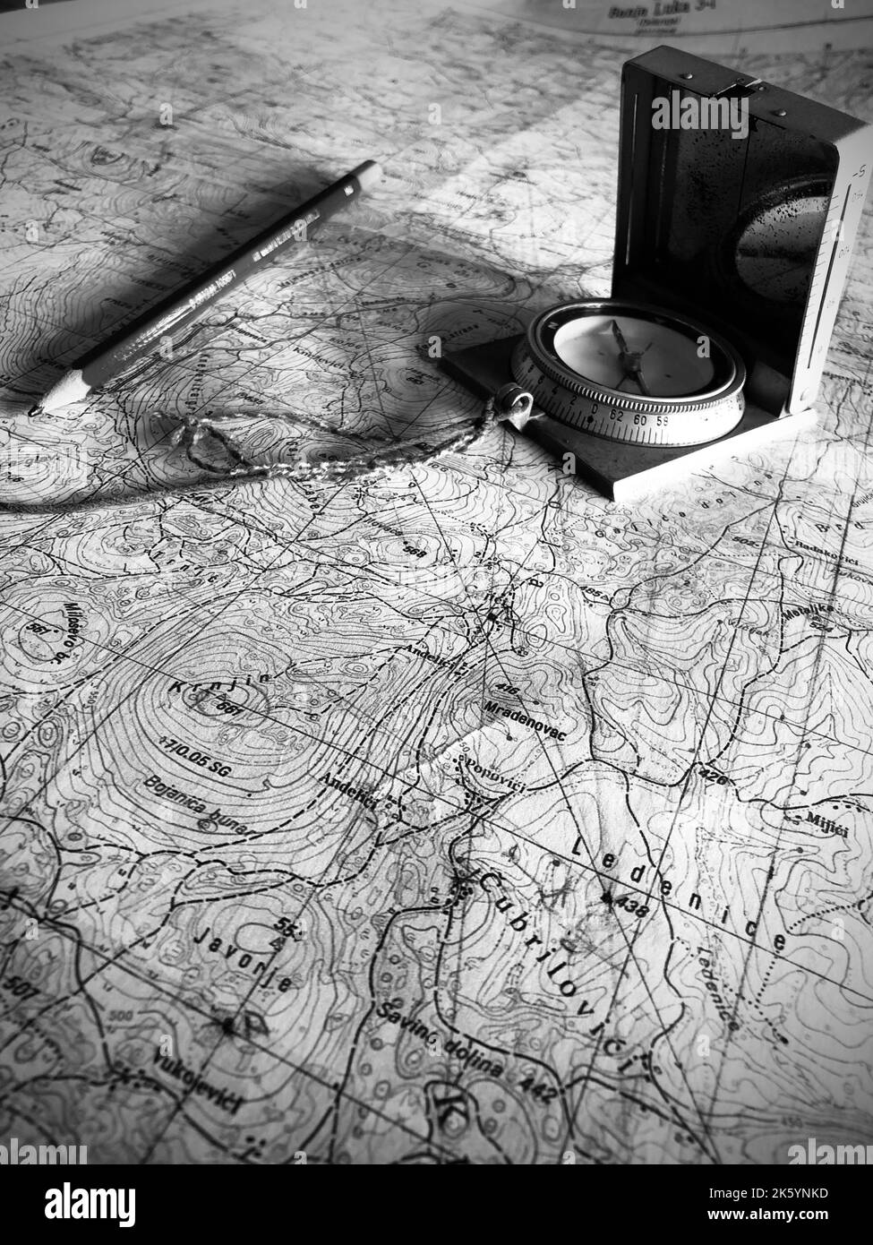A vertical grayscale shot of a compass and pencil on a vintage map ...