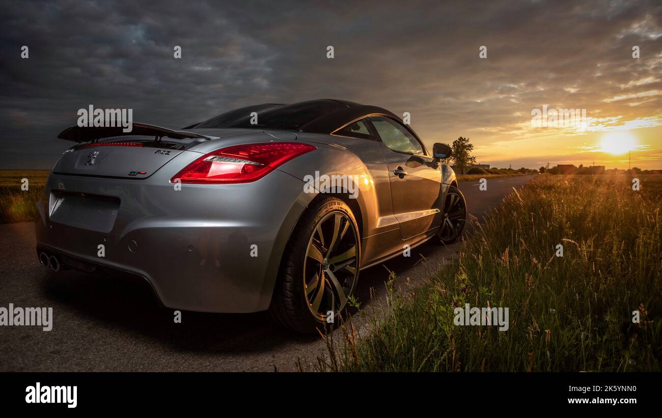 A modern Hyundai Genesis Coupe car on a field in a vibrant sunset sky ...
