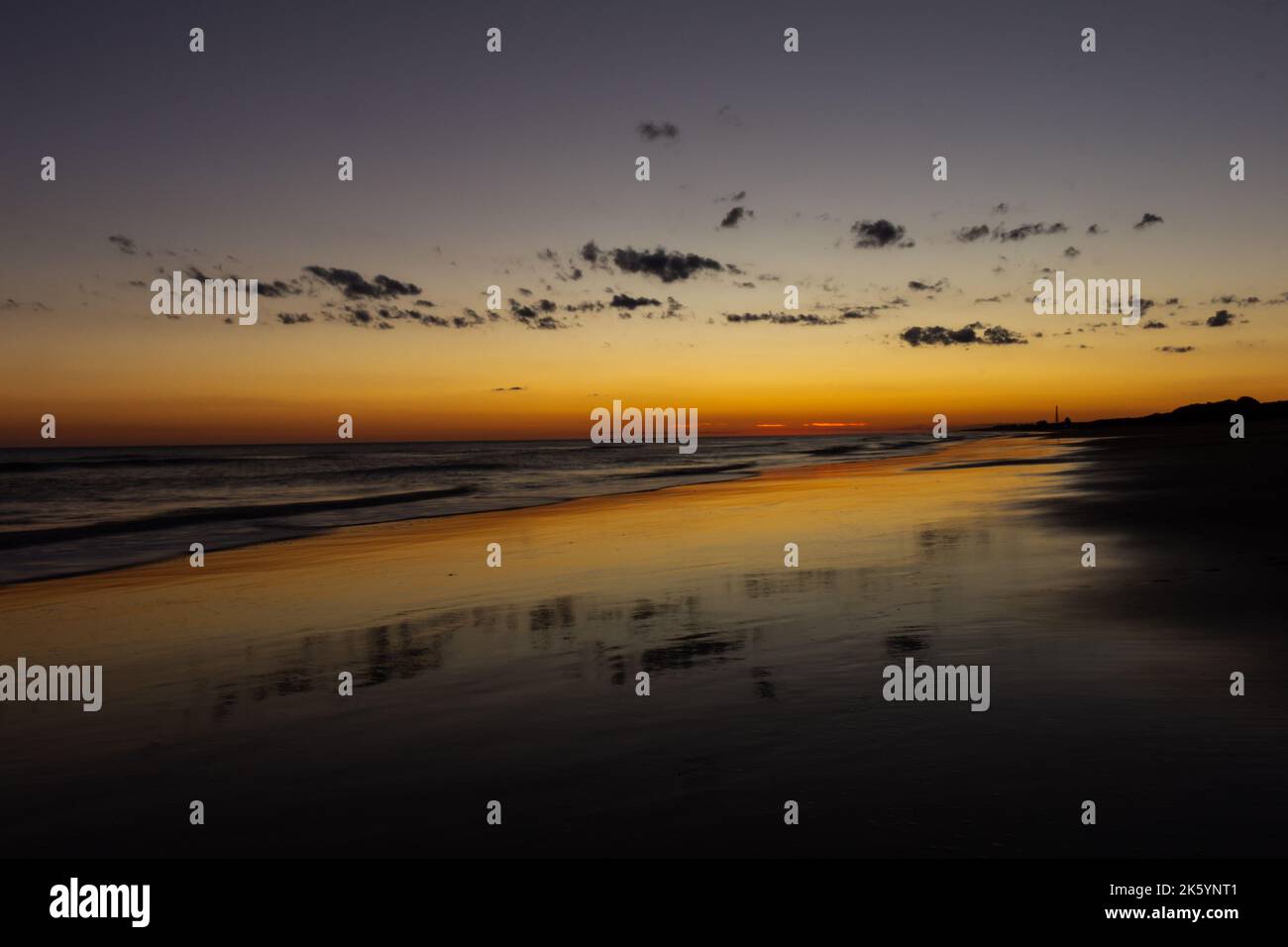 Incredible sunset on the beach. Sunlight reflects off the wet sand ...