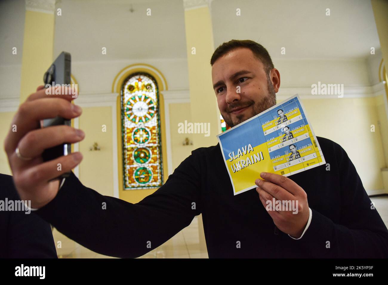 A man takes a selfie with a stamp dedicated to Ukrainian politician ...