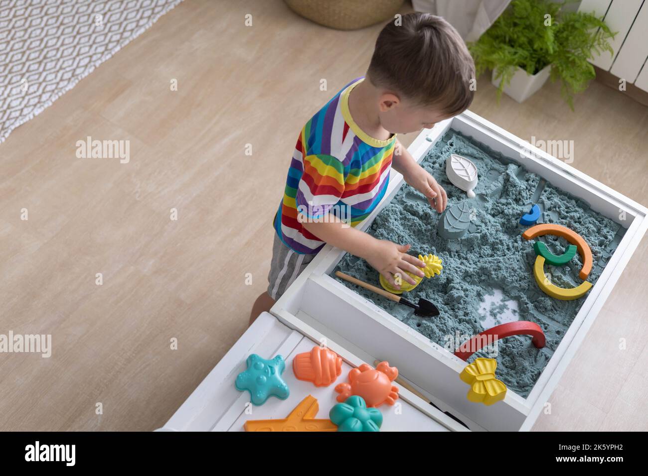 Overjoyed male kid playing kinetic sand early development education ...