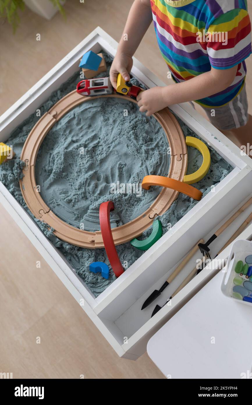 Cute baby boy confident playing railroad train toy on sand table ...