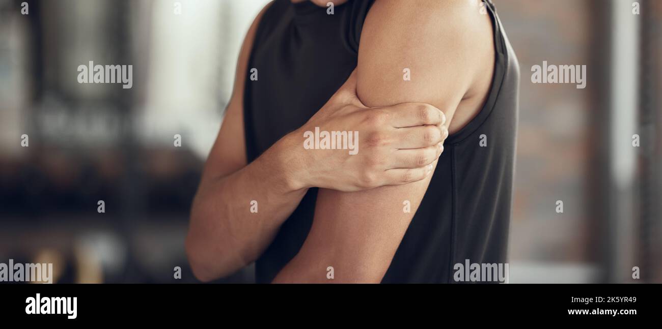 Hands of a bodybuilder with arm pain. Fit man with a sore bicep cropped. Active athlete touching ...