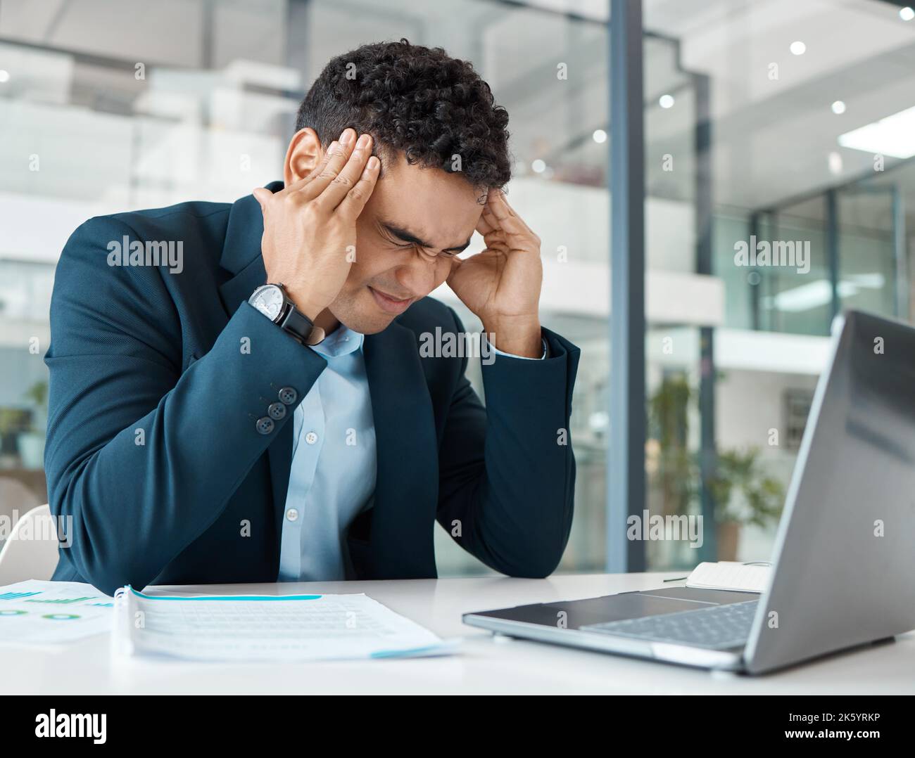 Young angry mixed race businessman suffering from a headache while ...