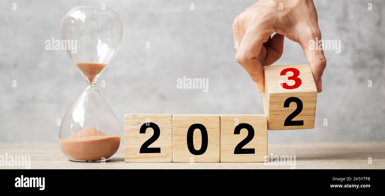 hand flipping block 2022 to 2023 text with hourglass on table ...