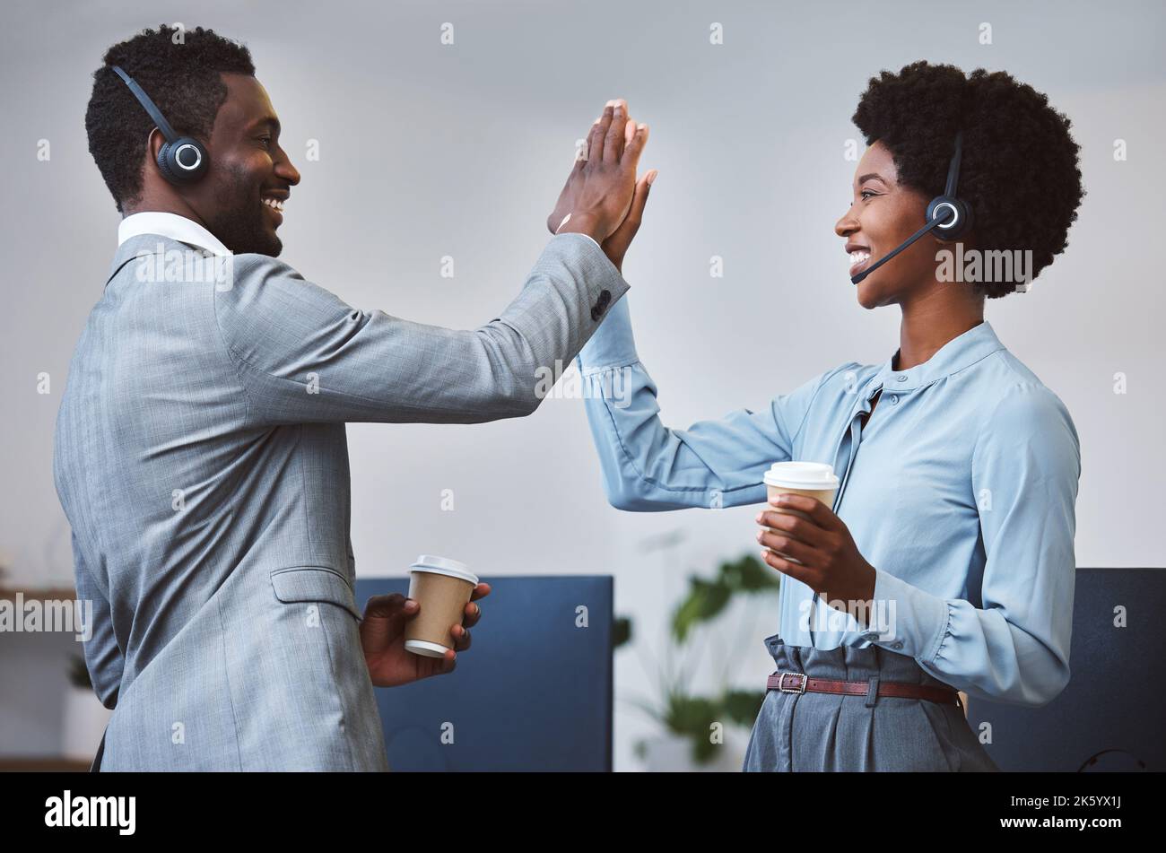 Two happy african american call centre telemarketing agents giving each ...