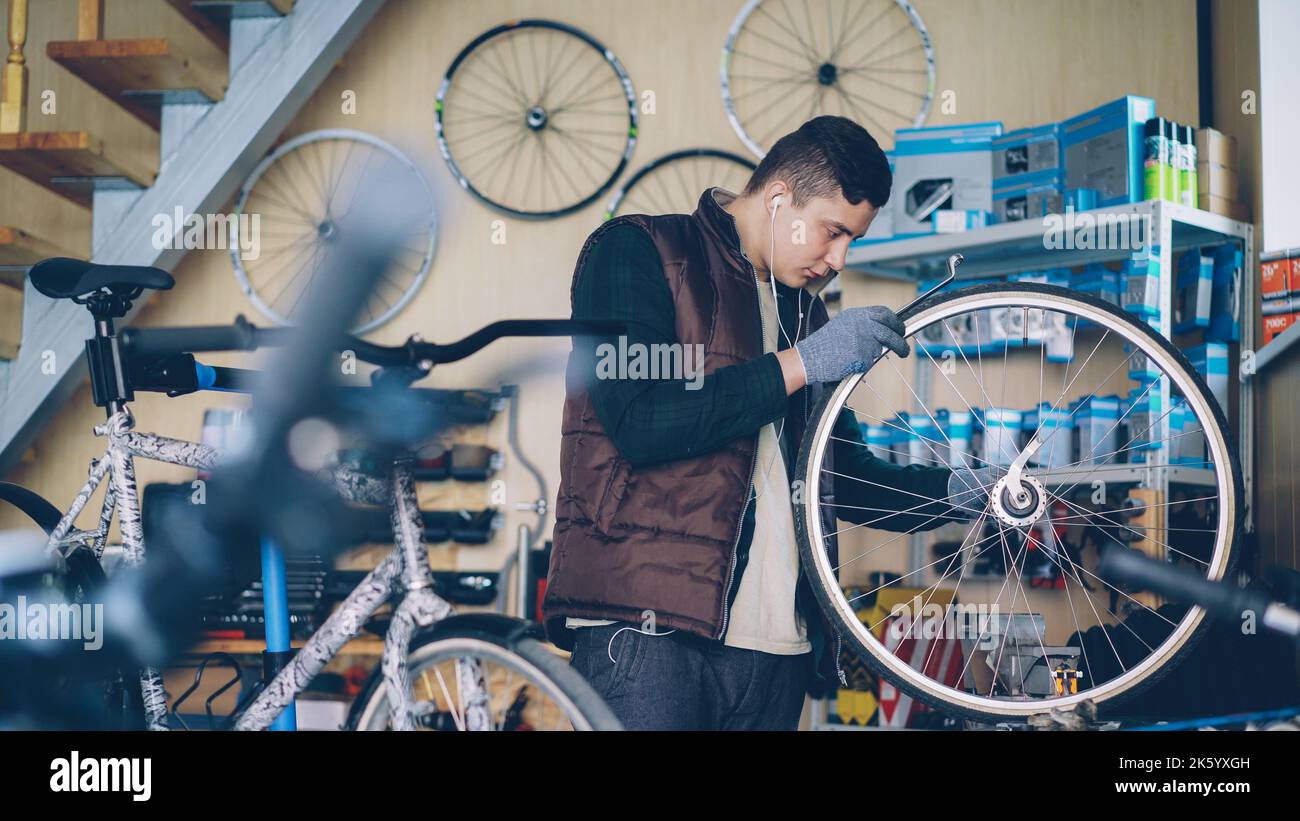 Self-employed male mechanic is repairing bicycle wheel with wrenches ...
