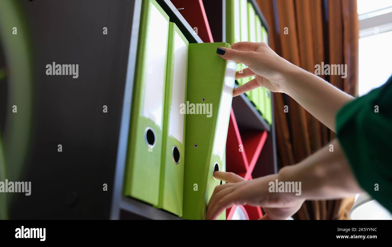 Female hands taking off folder with documents from shelf Stock Photo ...