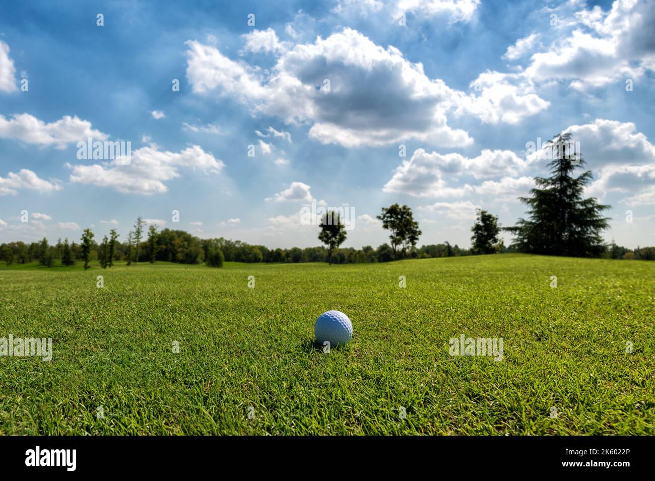 Lush green grass of gold club field under blue sky with white ball on ...