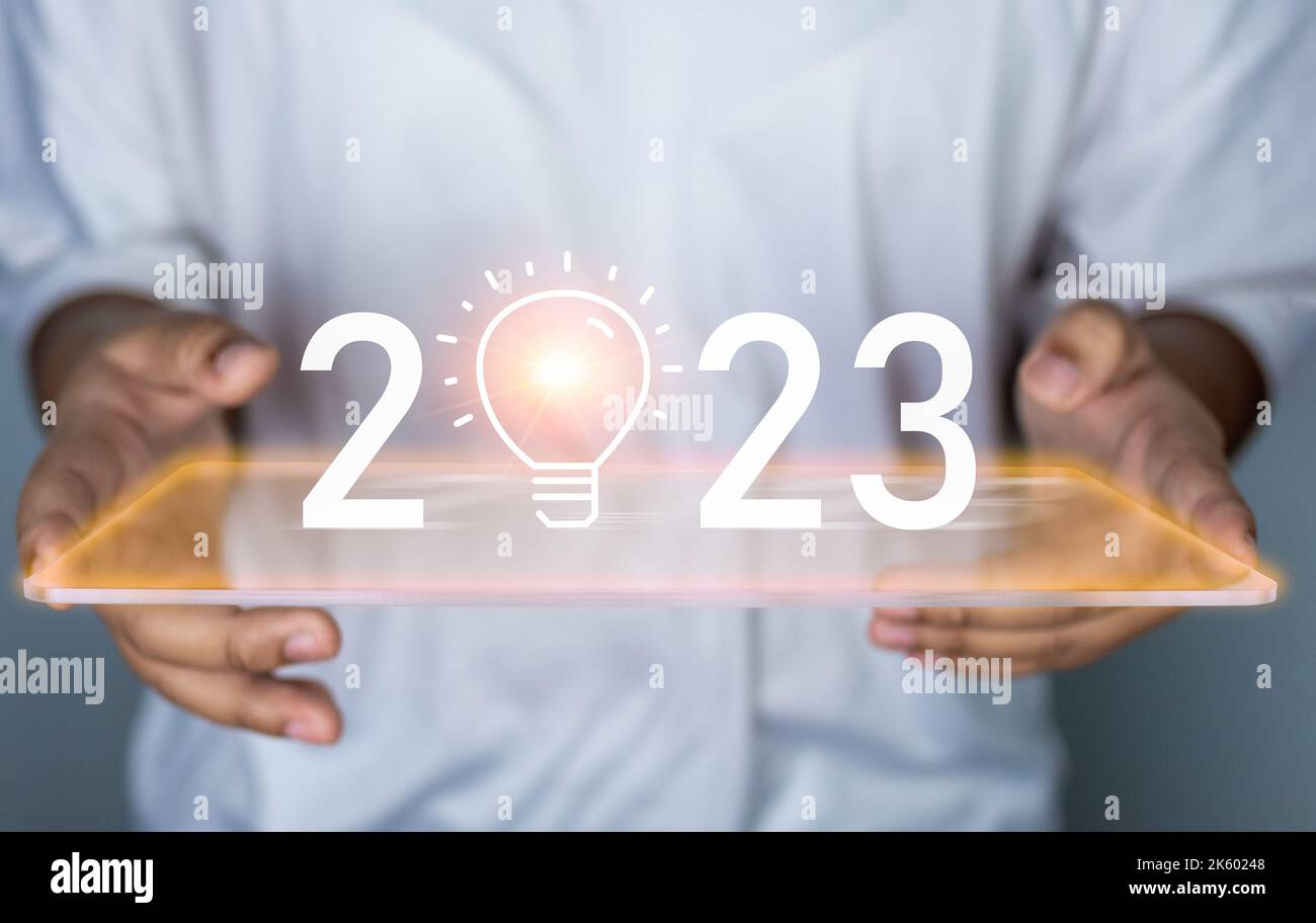 Woman holding 2023 icon and light bulb. Represents the goal setting for ...