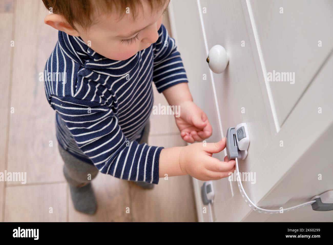 Baby opens the child lock on the closed drawer of the cabinet. Toddler ...