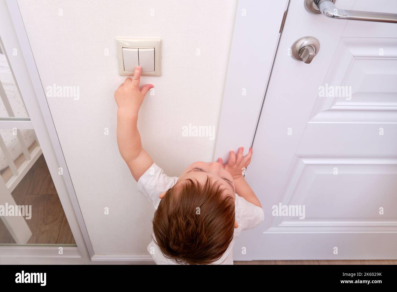 Toddler baby reaches for the light switch, child hand turns on the lamp ...