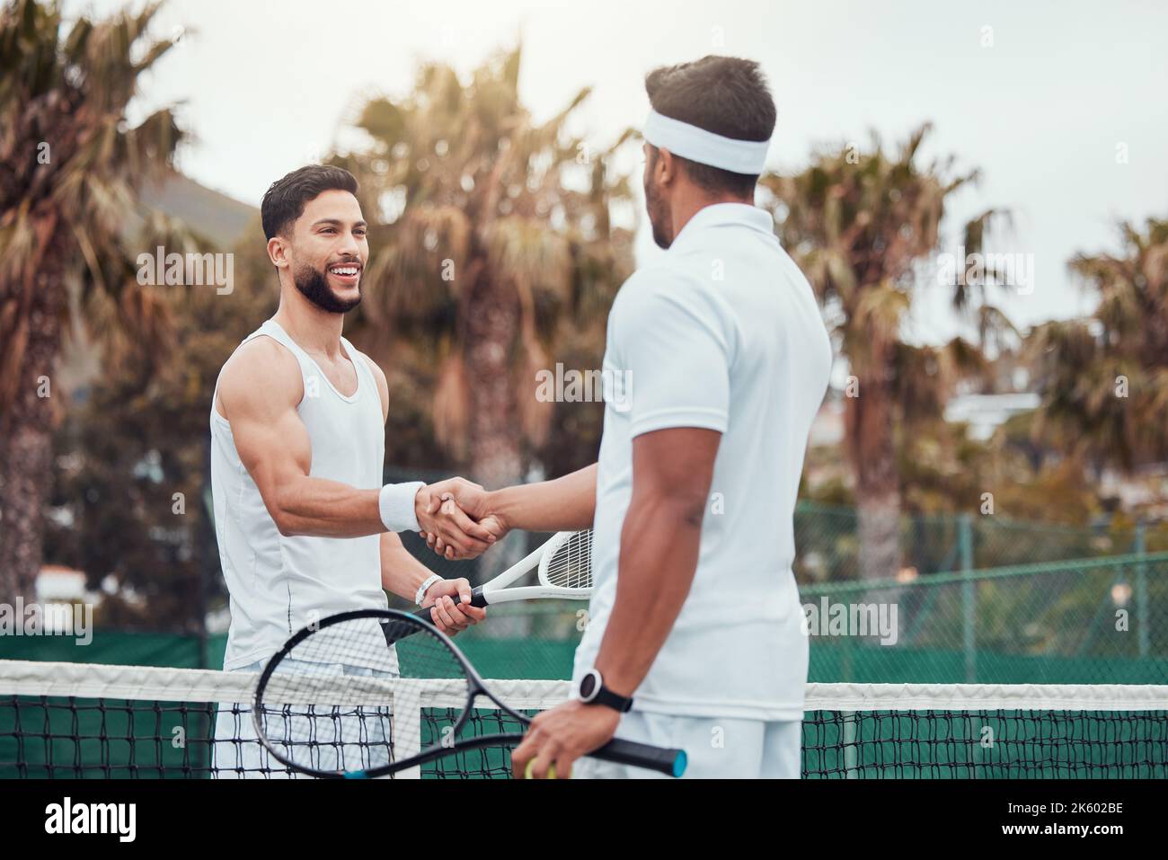 Two ethnic tennis players shaking hands before playing court game ...