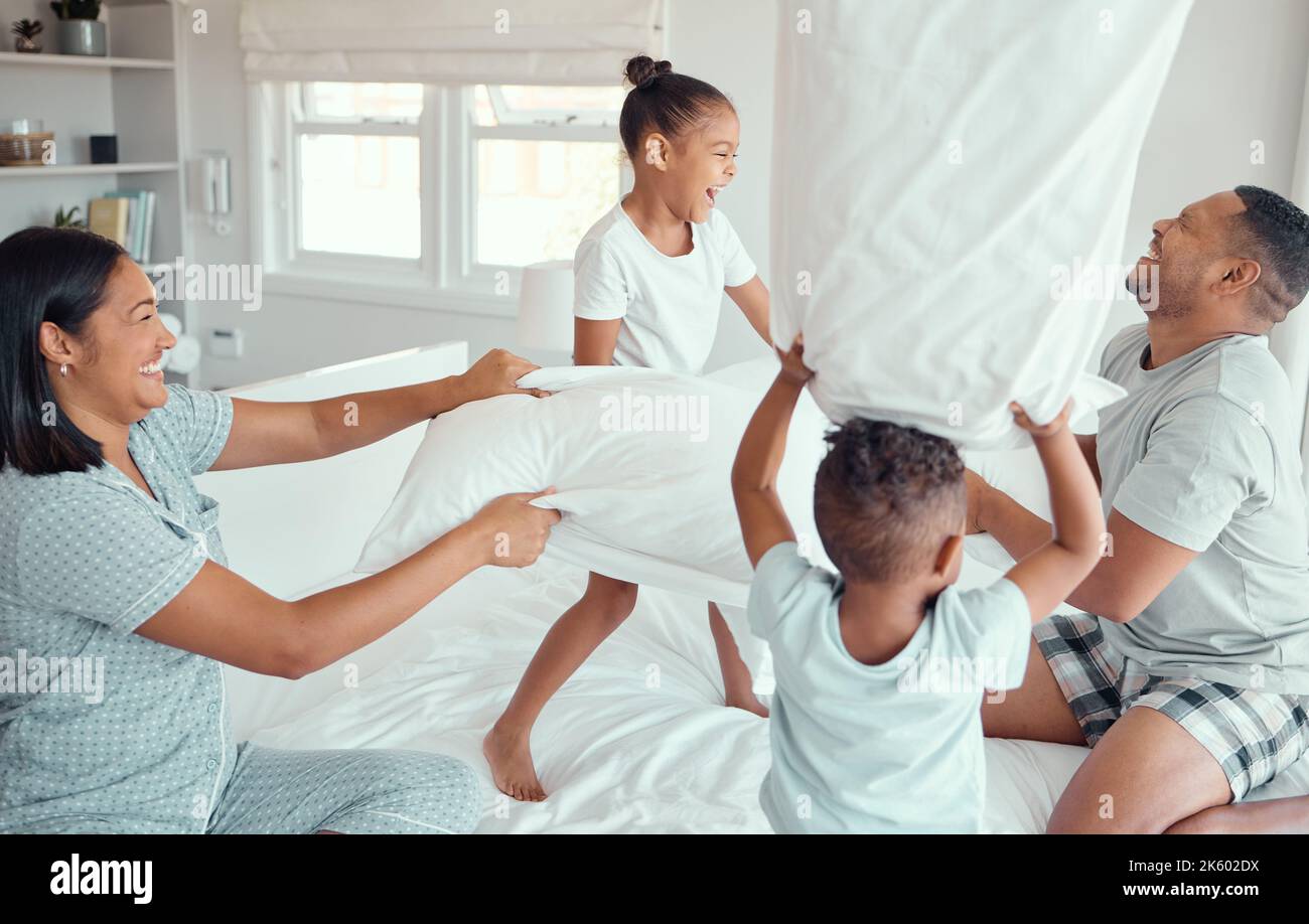 Two happy children laughing and enjoying pillow fight with parents in ...