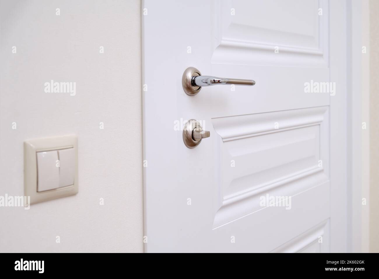 A white door with a lock in the home room and a light switch. Metal ...