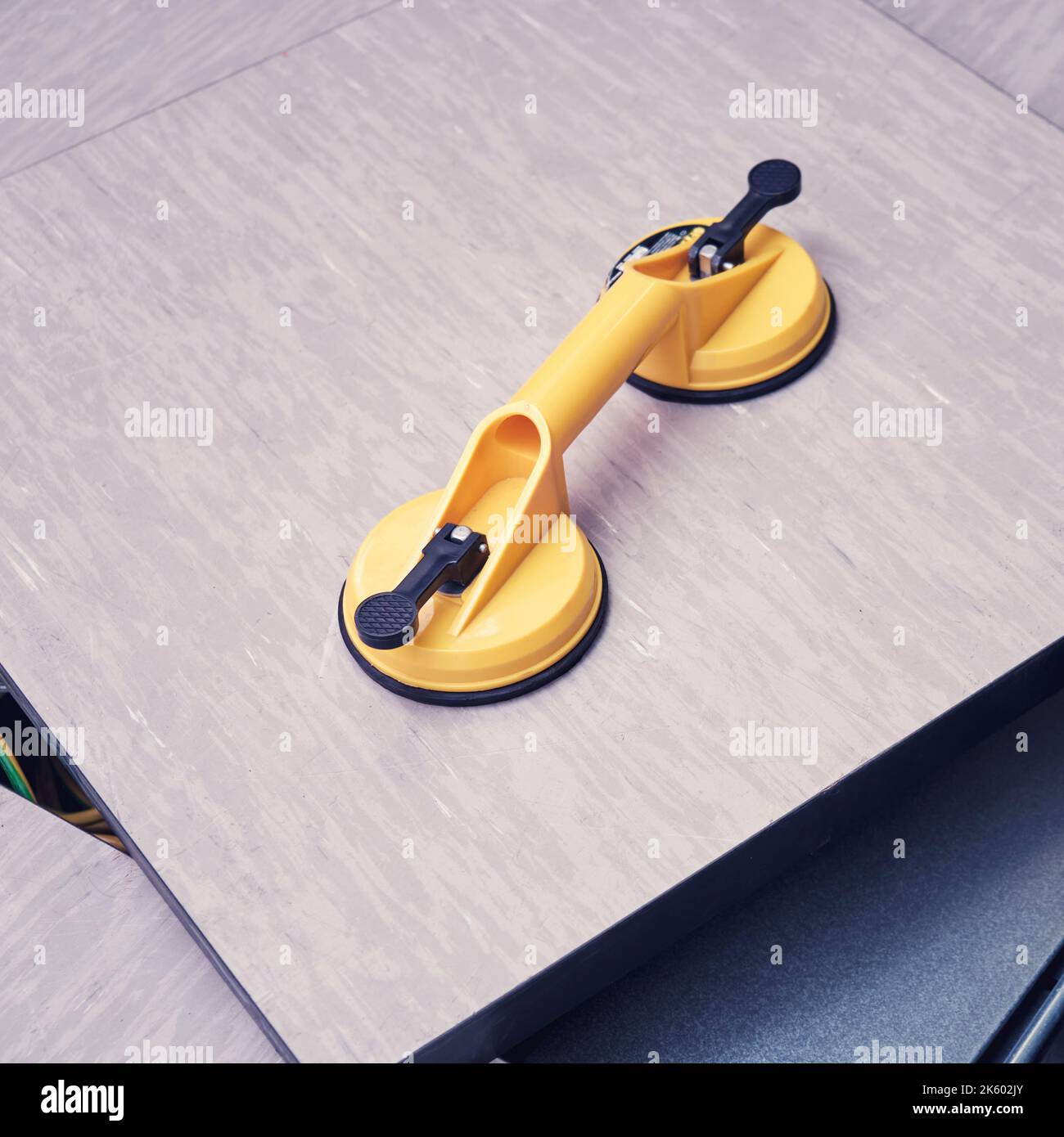 Yellow handheld device with vacuum suction cups for lifting floor ...