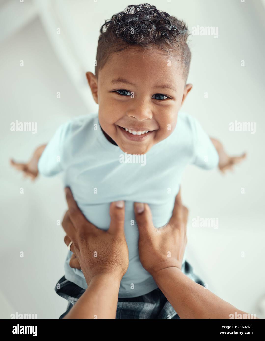 Happy little mixed race boy lying in fathers arms while looking at the camera and smiling ...