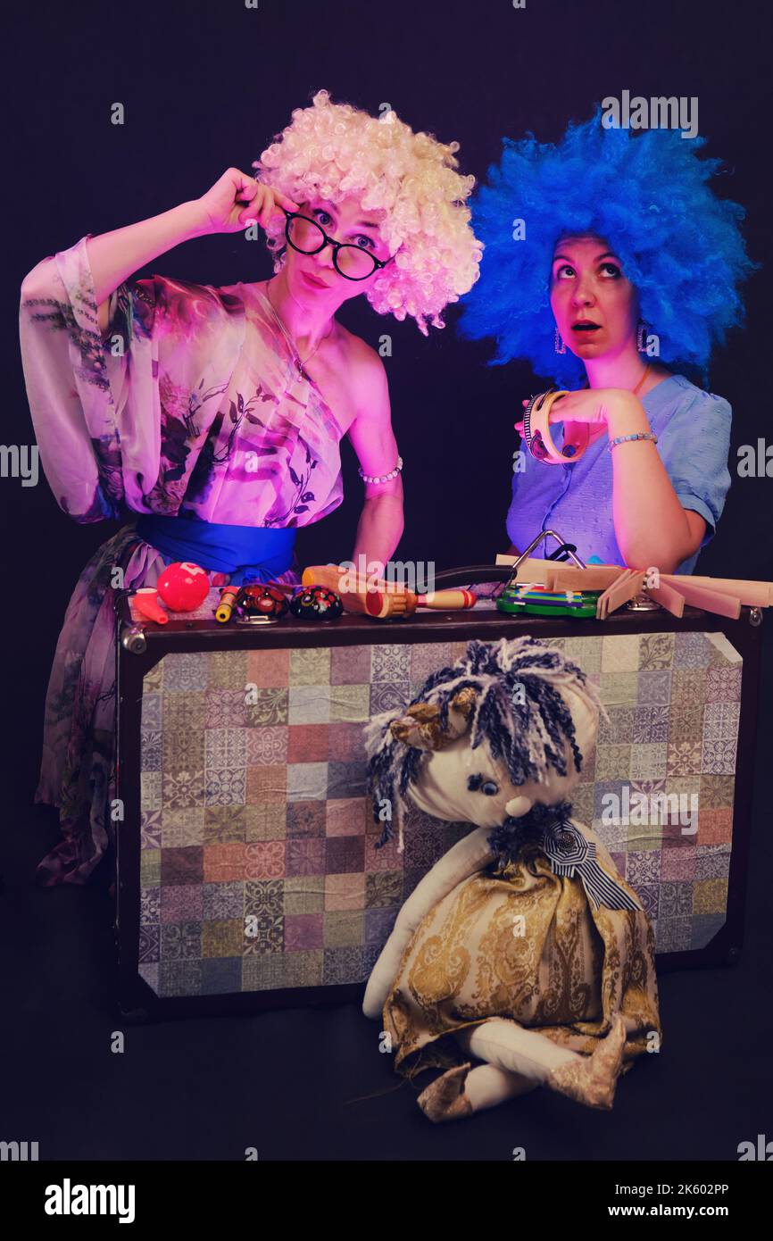 Happy women in funny wigs give a musical performance on a studio black ...
