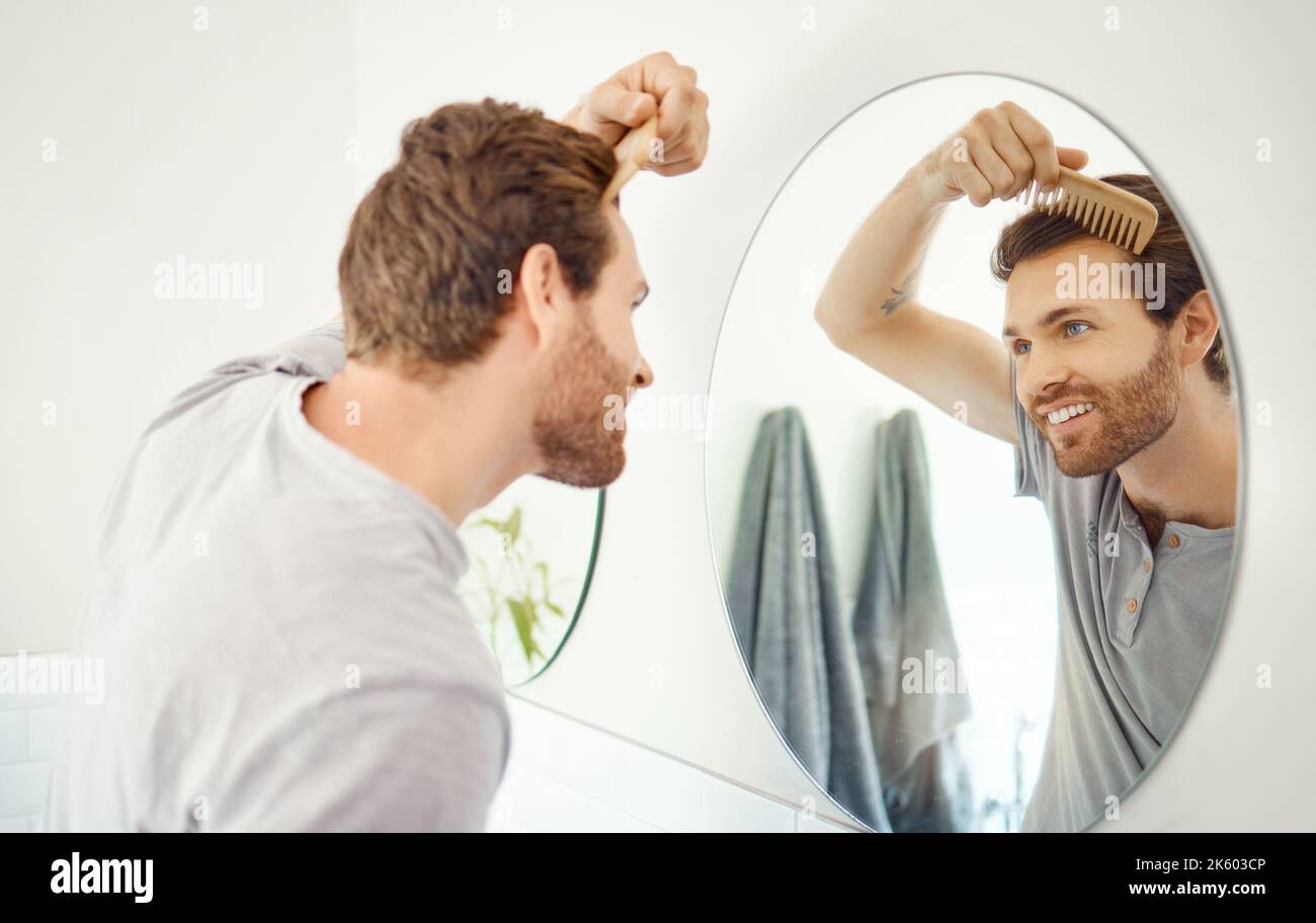 One handsome man combing his hair in a bathroom at home. Caucasian male ...