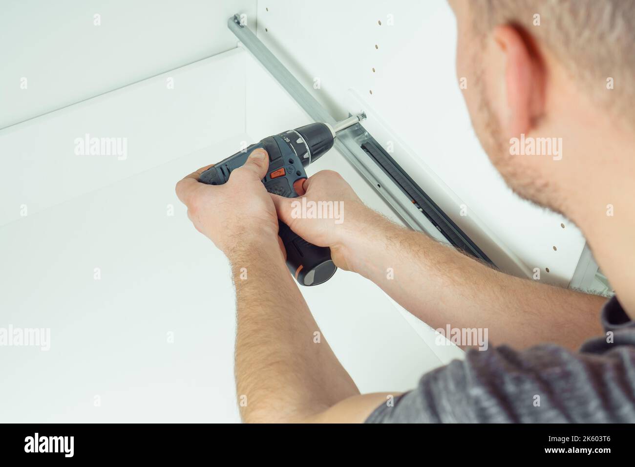 Male hands hold cordless electric screwdriver, screw to fix rail ...