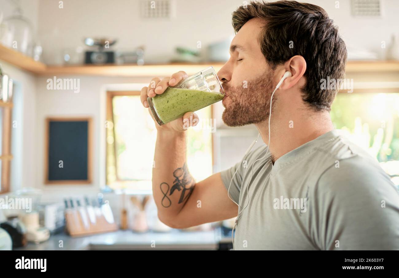 One fit young caucasian man drinking a glass of healthy green detox ...