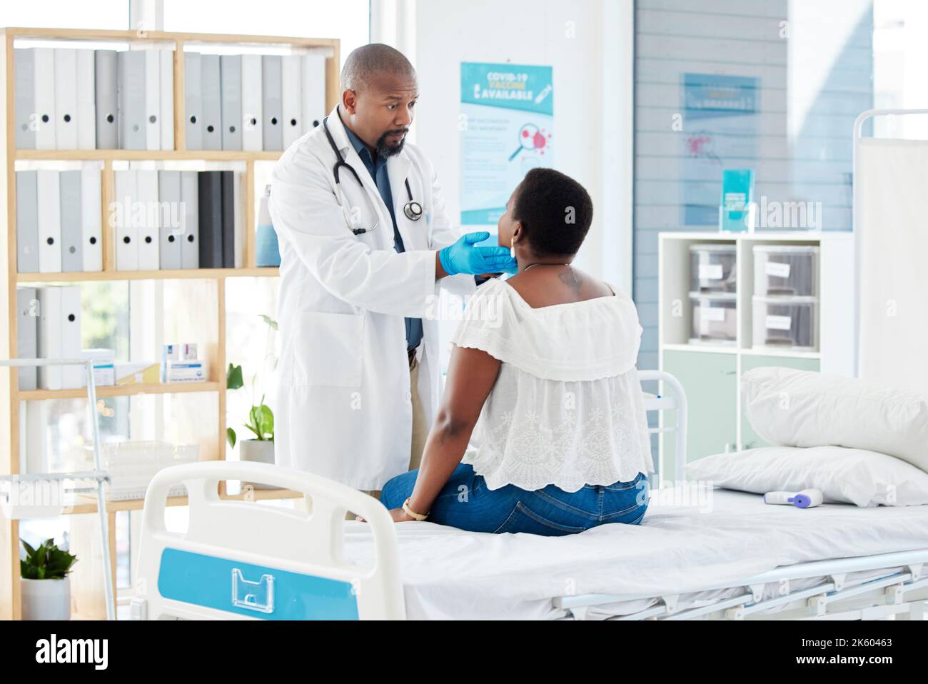 Doctor feeling a patients neck. Mature doctor in a consult with a ...