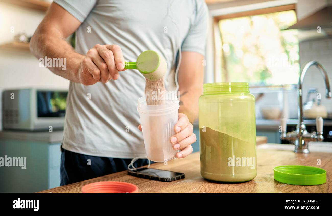 Closeup of one caucasian man pouring a scoop of chocolate whey protein ...
