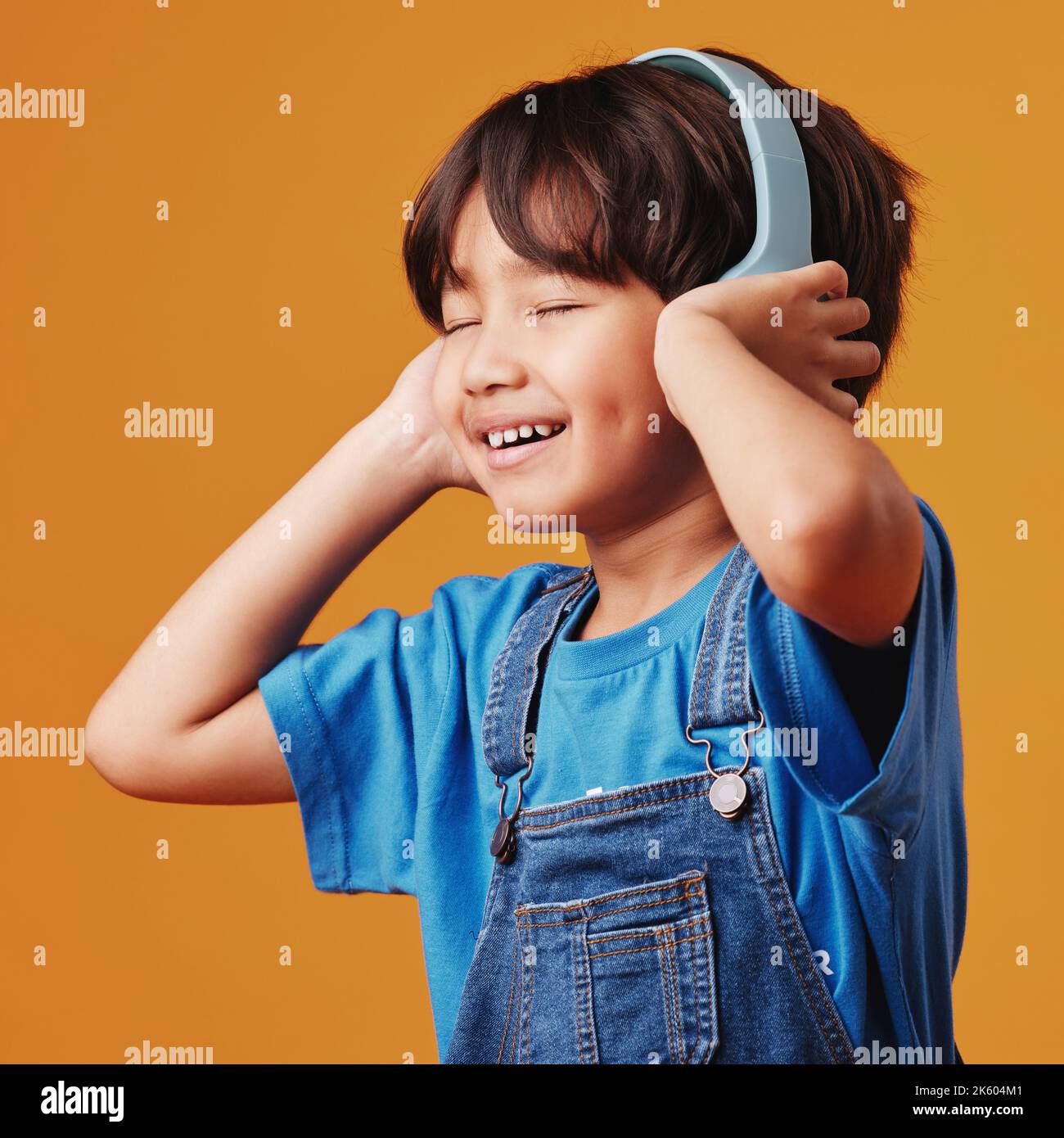 A cute little asian boy enjoying listening to music while wearing ...
