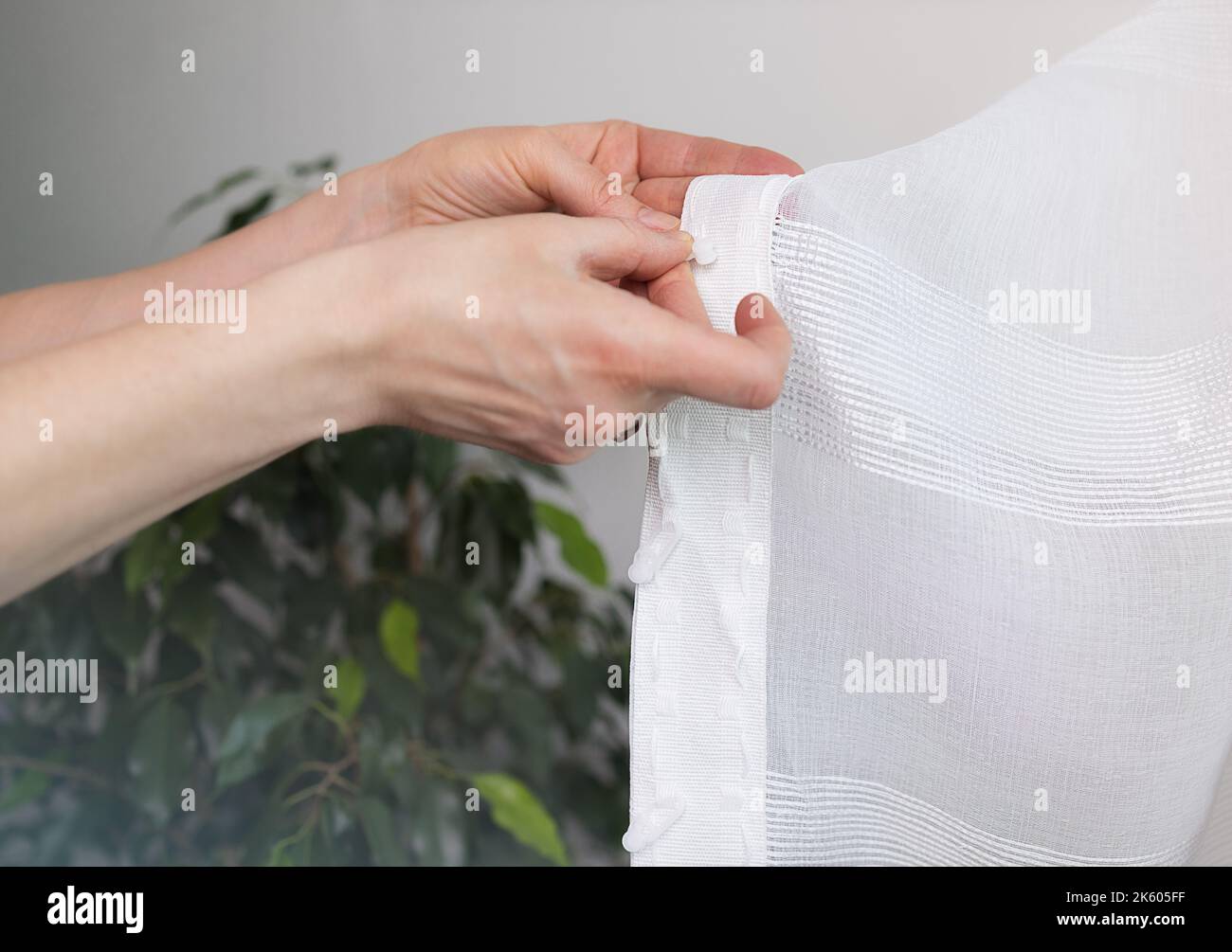 close-up, woman's hands show how to sew a curtain with a special tape ...