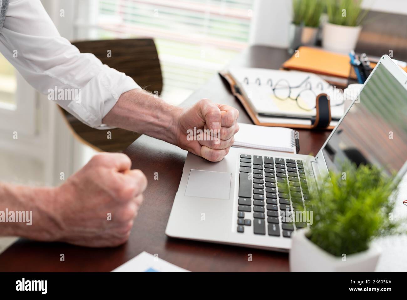Angry businessman hitting his desk with his clenched fists Stock Photo ...