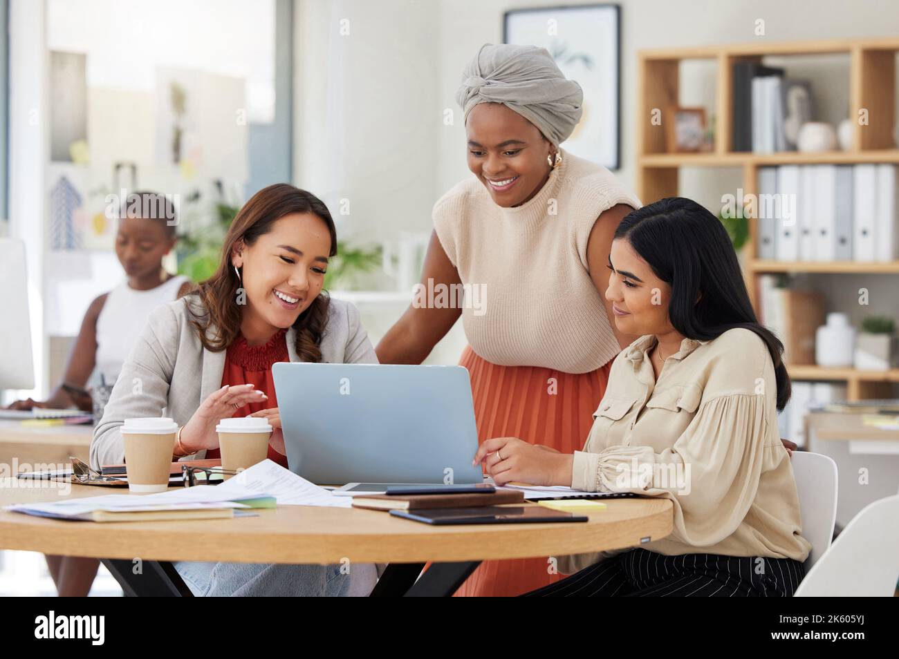 Diverse group of smiling business women using a laptop for a brainstorm ...