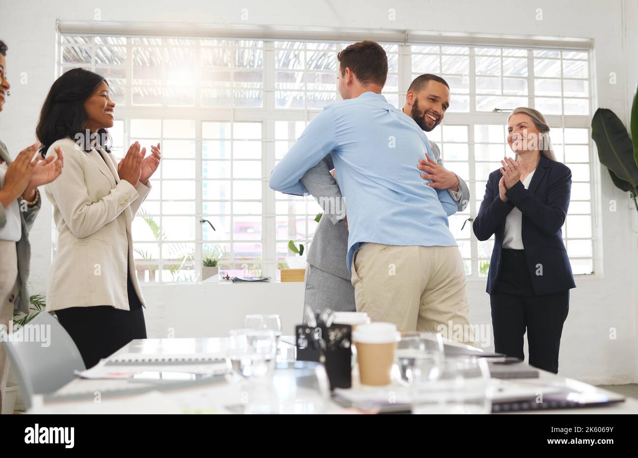 Businessmen hugging each other in support and unity while colleagues ...