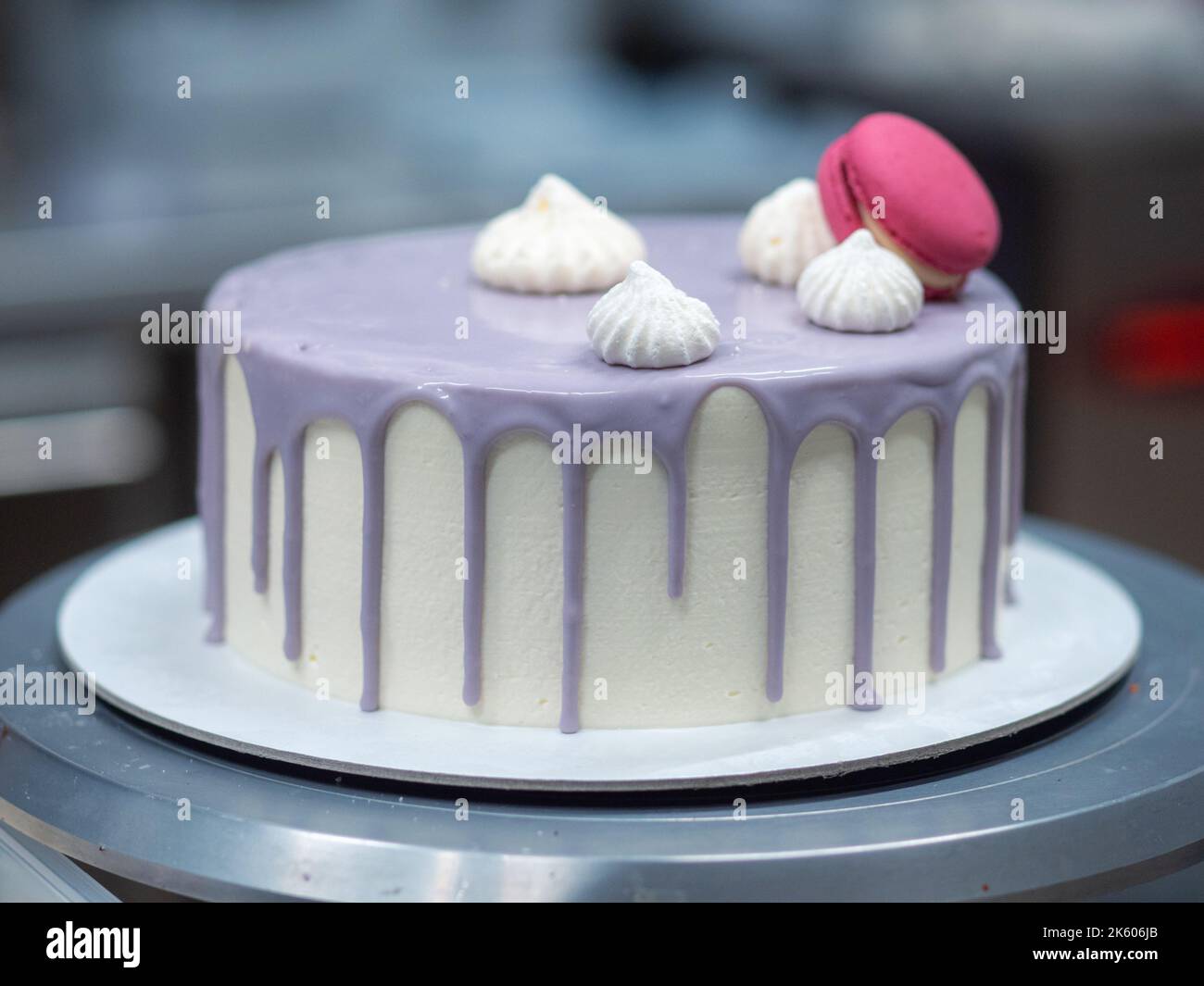 frosted drip cake on stand while designer works on topping Stock Photo ...
