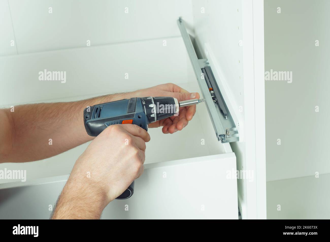 Male hands hold cordless electric screwdriver, screw to fix rail ...