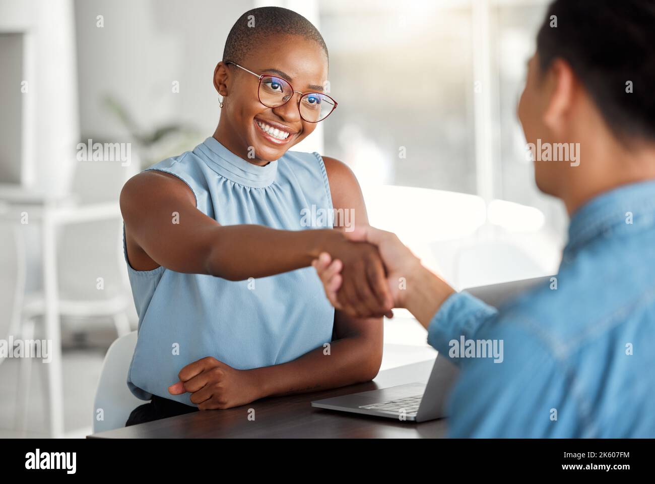 Two cheerful businesspeople shaking hands in a interview together at ...