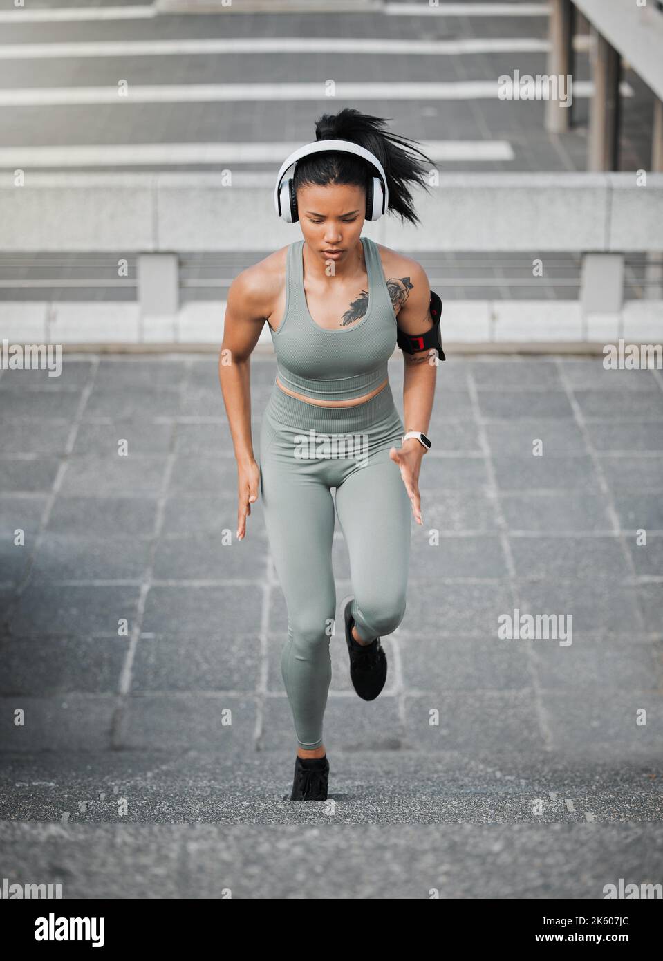 Young mixed race female wearing gym wear and wireless headphones while ...