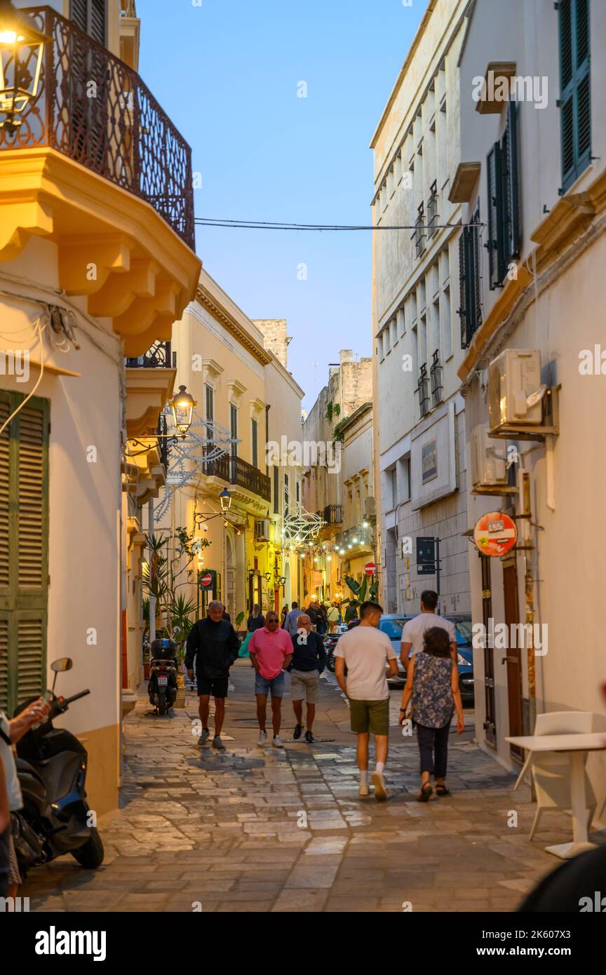 Tourists and locals walking along a typical narrow and cobbled street ...