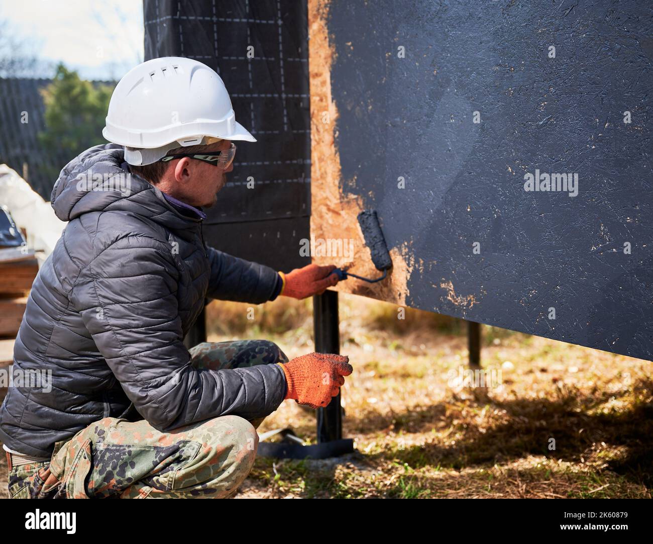 Male painter using paint roller, doing exterior paint work in a black ...